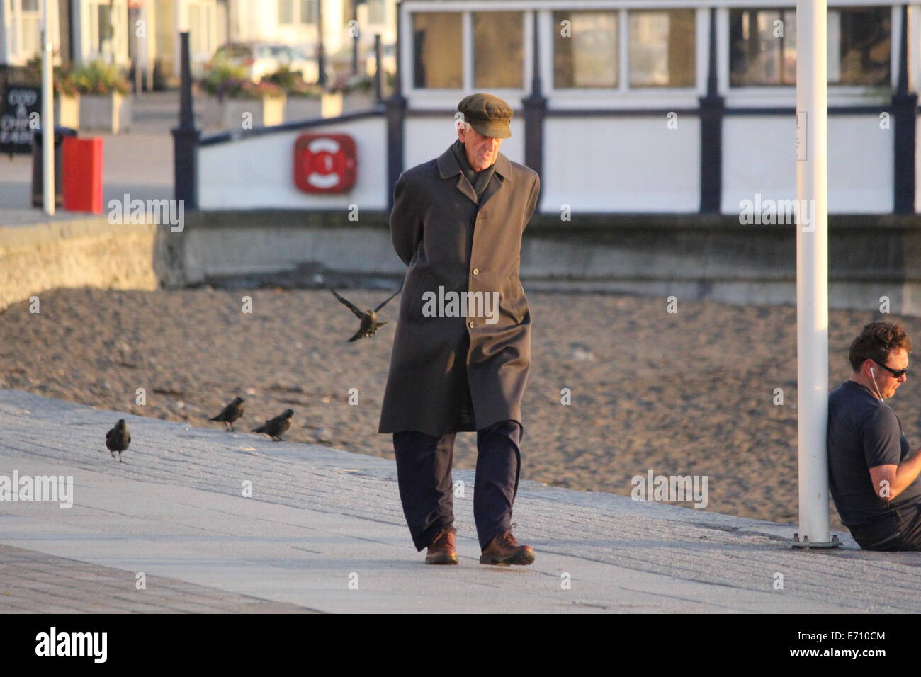 AN ELDERLY MAN TAKES AN EVENING WALK PAST THE BANDSTAND IN ABERYSTWYTH ...