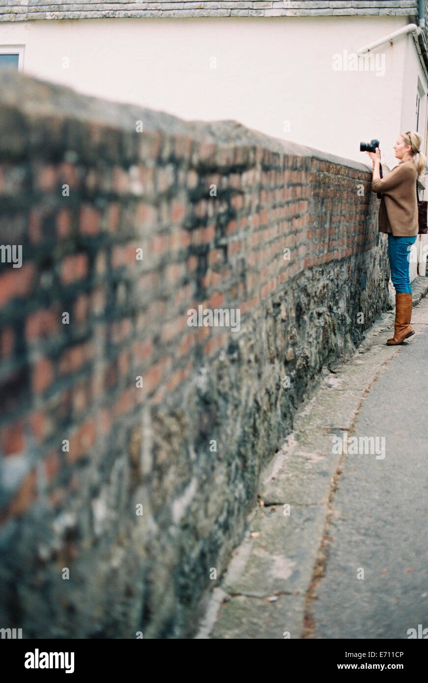 A woman looking over a wall and holding a camera Stock Photo - Alamy