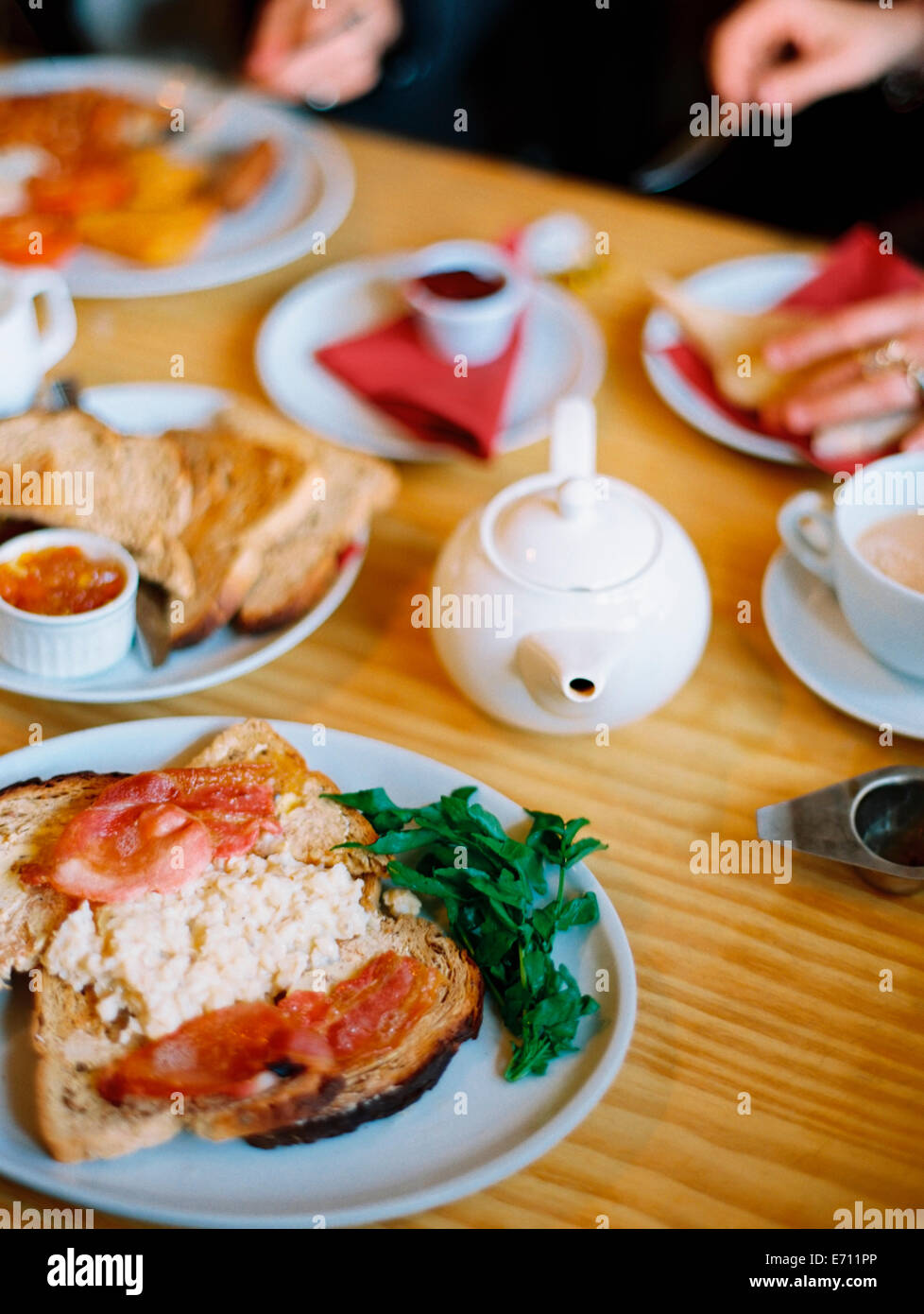 A table covered with plates of food. A cooked breakfast of bacon, eggs ...