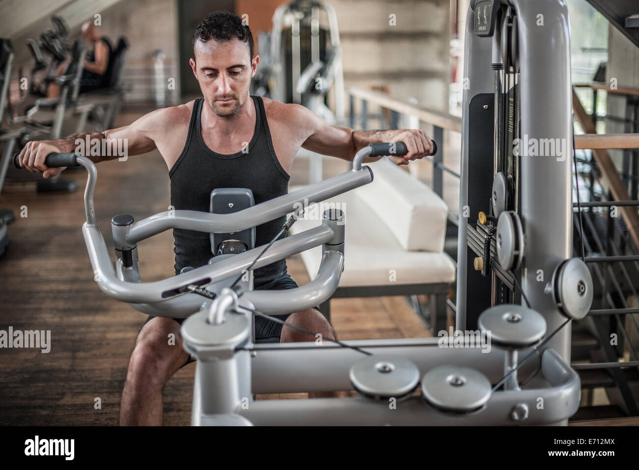 Mid adult man using weight equipment Stock Photo - Alamy