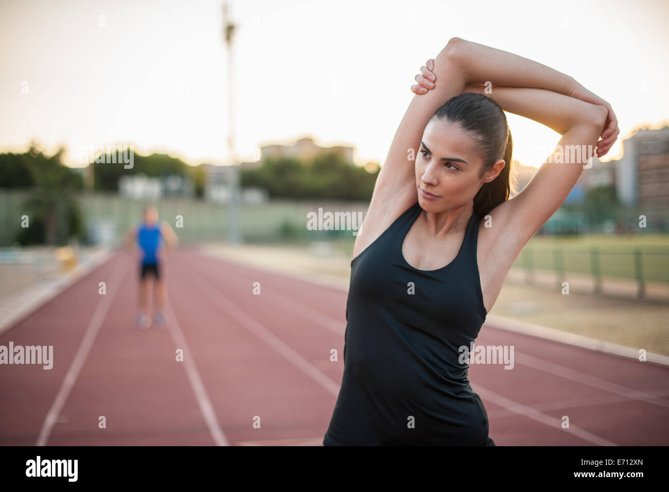 Young woman stretching arm on running track Stock Photo - Alamy