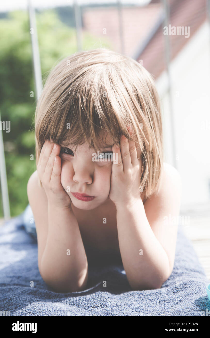 Portrait of sad little girl lying on towel on balcony Stock Photo - Alamy