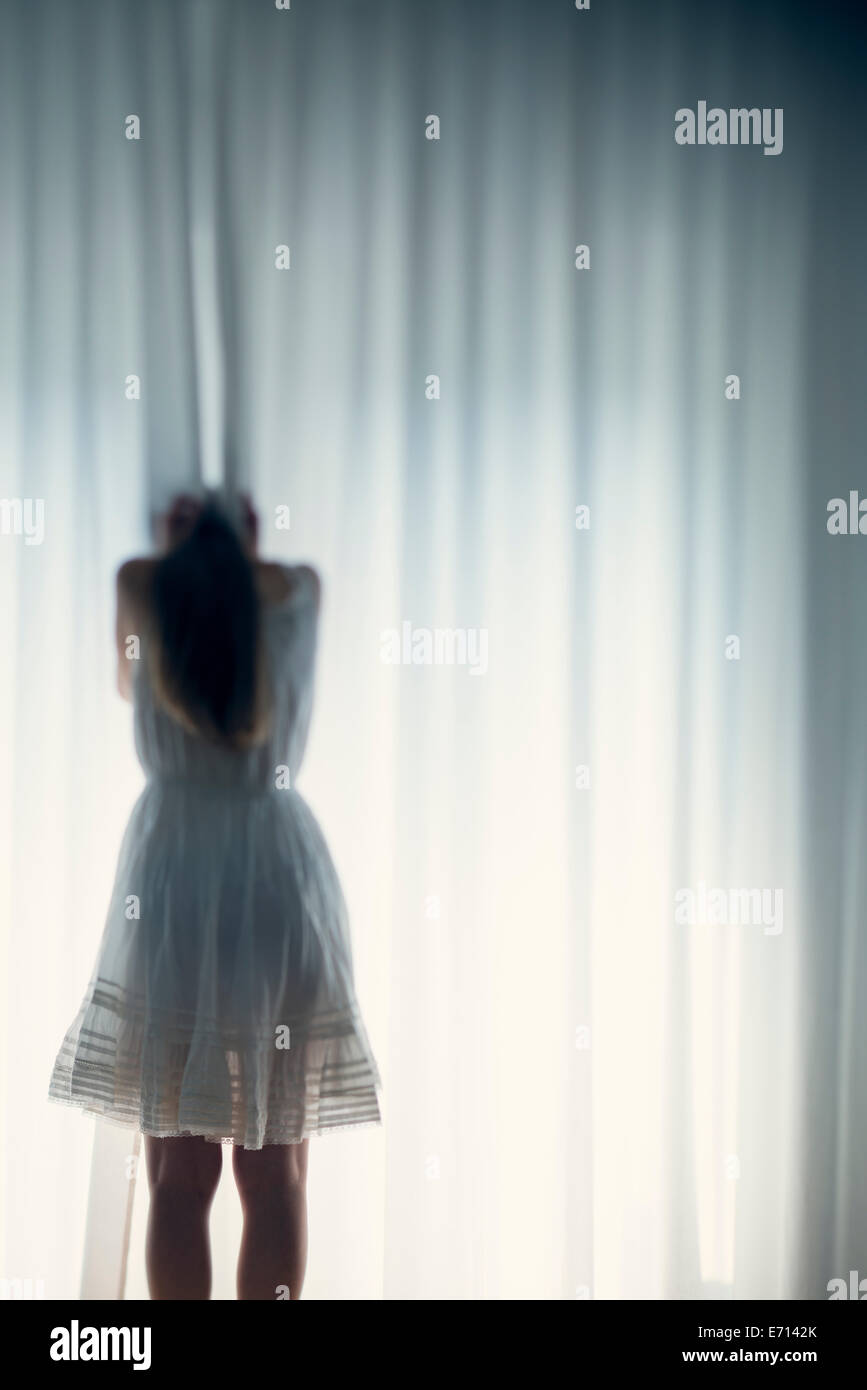 Young woman hiding her face behind a white curtain, back view Stock ...