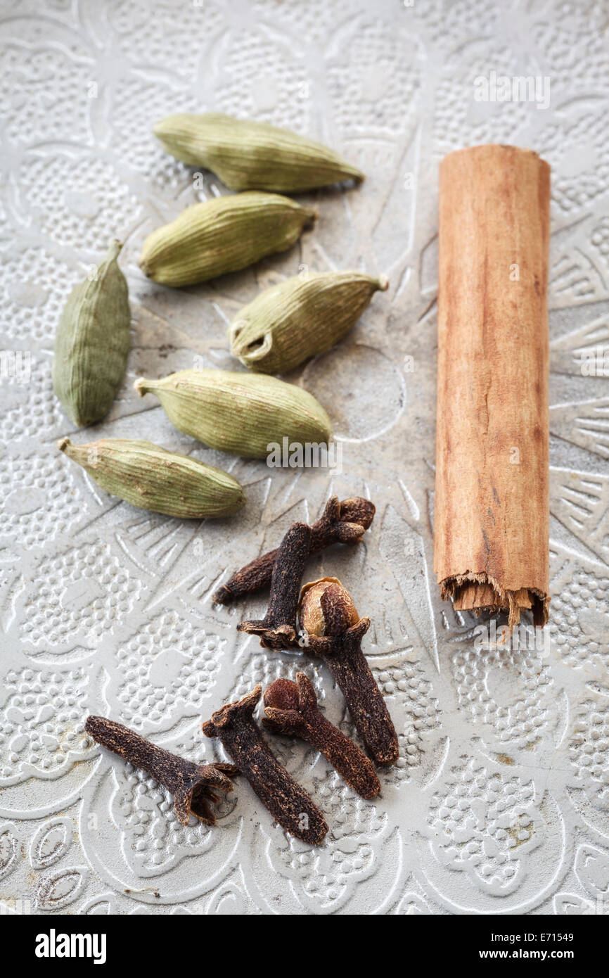 Cardamom capsules, cloves and cinnamon stick on metal plate, close-up ...