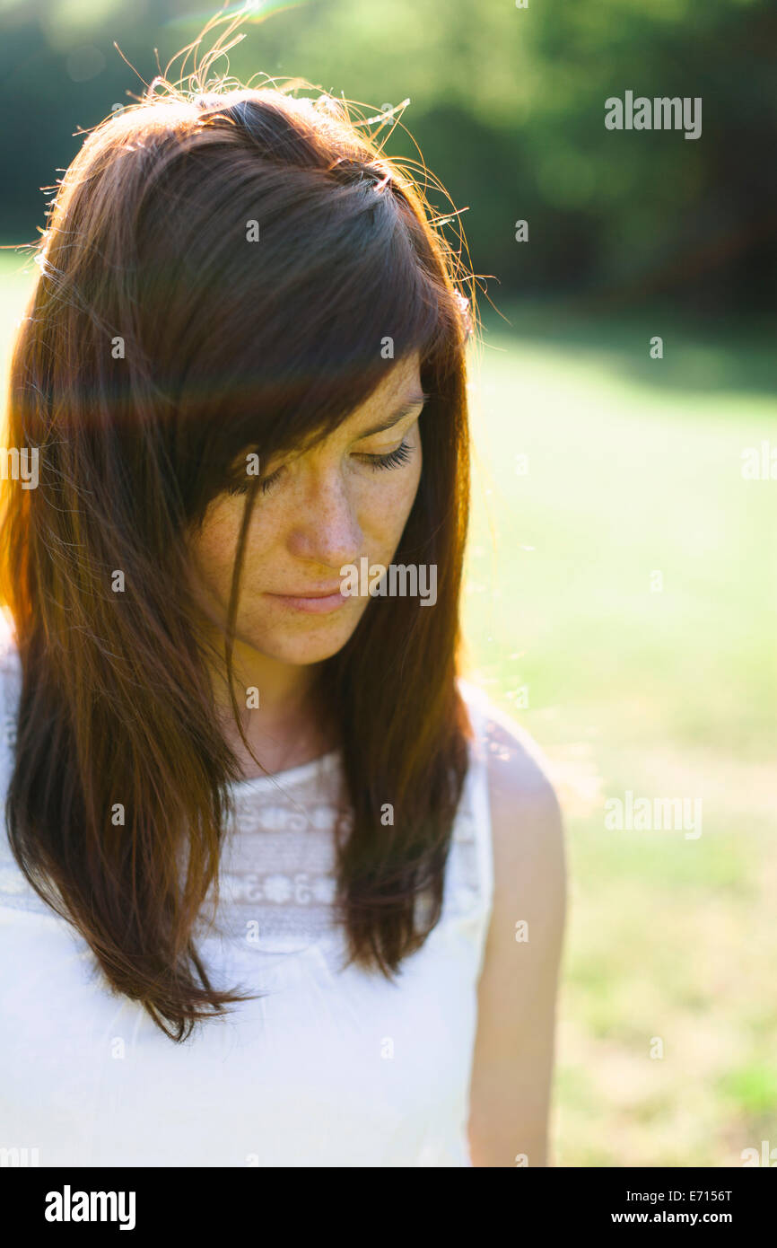 Brunette woman outdoors looking down Stock Photo - Alamy