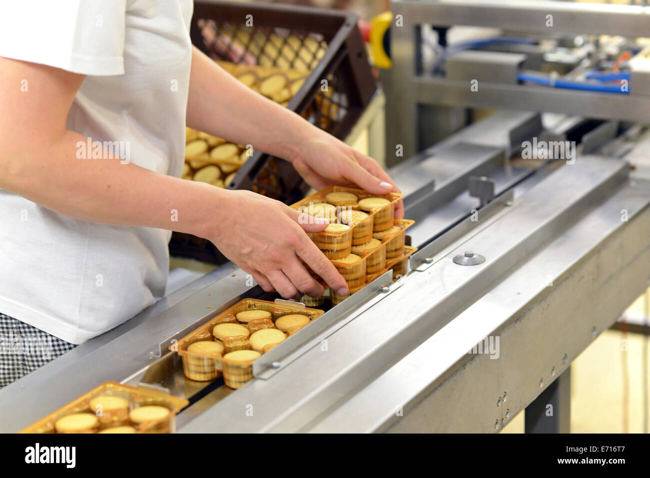 Germany, Saxony-Anhalt, woman taking pack of cookies from production ...