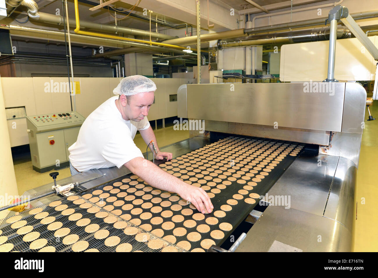 Germany, Saxony-Anhalt, man controlling cookies in a baking factory ...