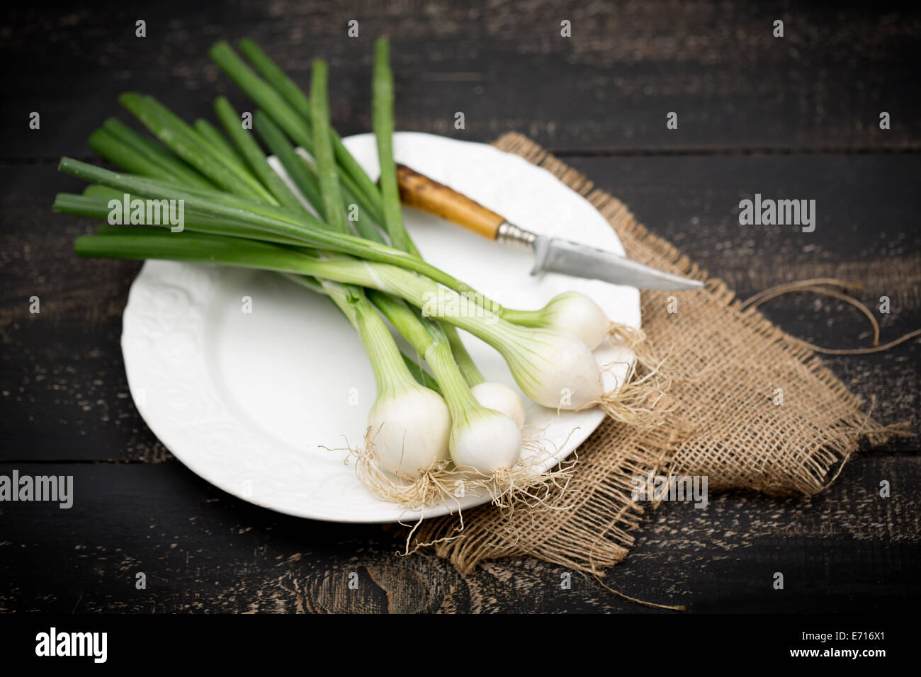 Spring onions and knife on plate Stock Photo - Alamy