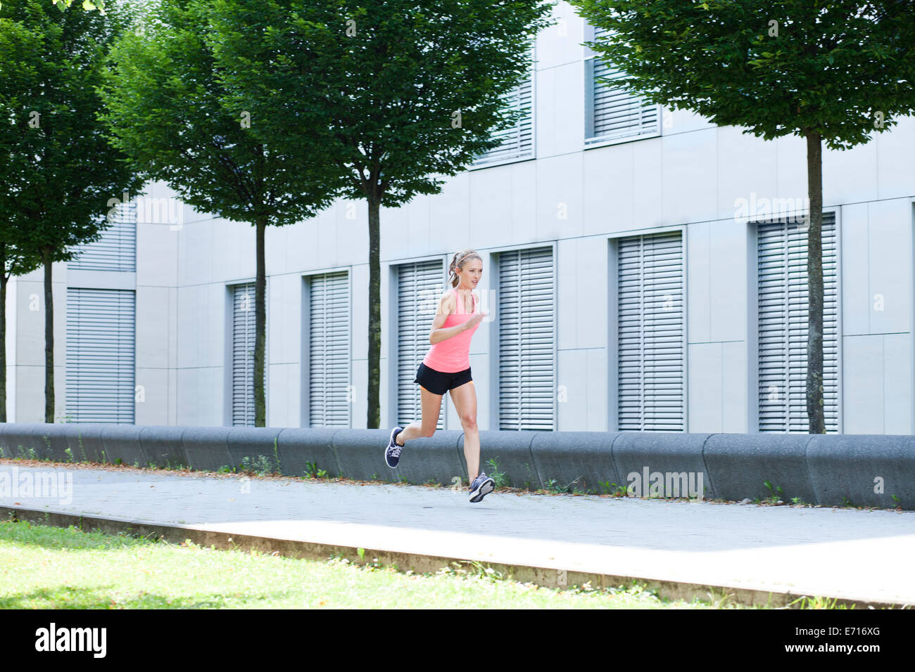Young woman jogging in front of facade of an office building Stock ...