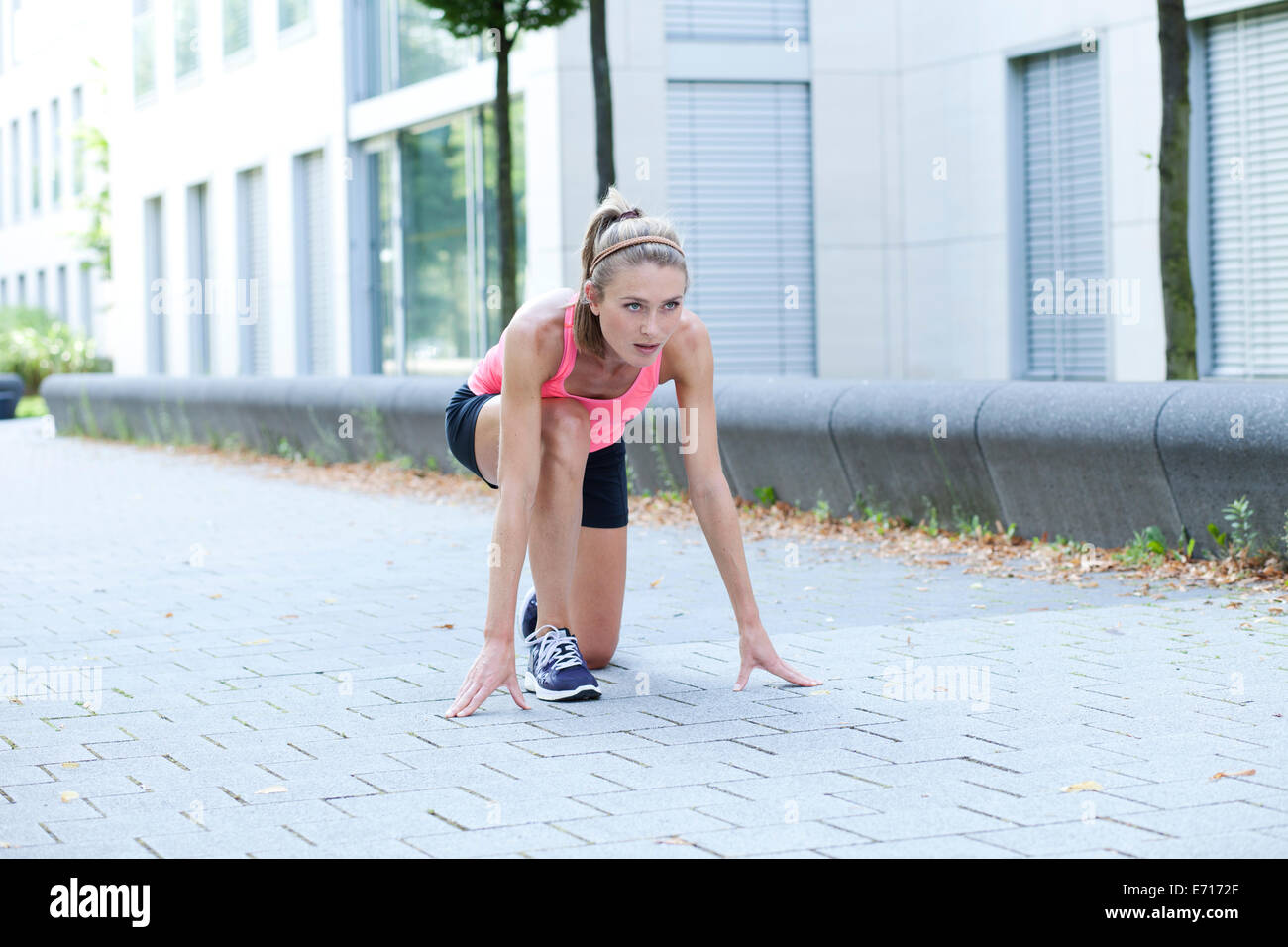 Young woman in start position in front of an office building Stock ...