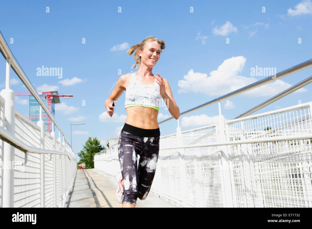 Germany, Munich, Female jogger running on a bridge Stock Photo - Alamy