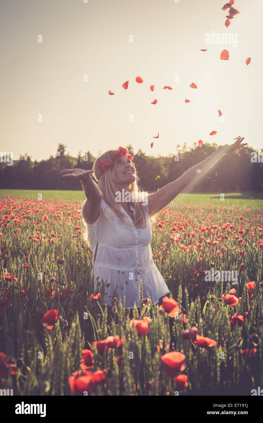 Woman jumping in a poppy field throwing petals in the air Stock Photo ...