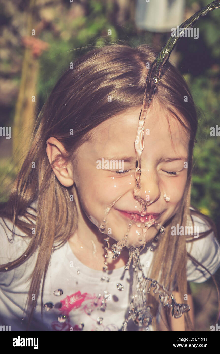Little girl refreshing her face with a jet of water Stock Photo - Alamy