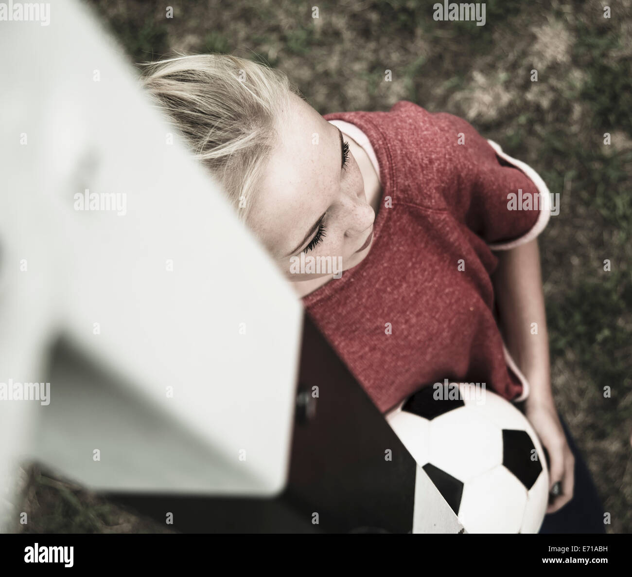 Teenage girl with football standing on soccer field, elevated view ...