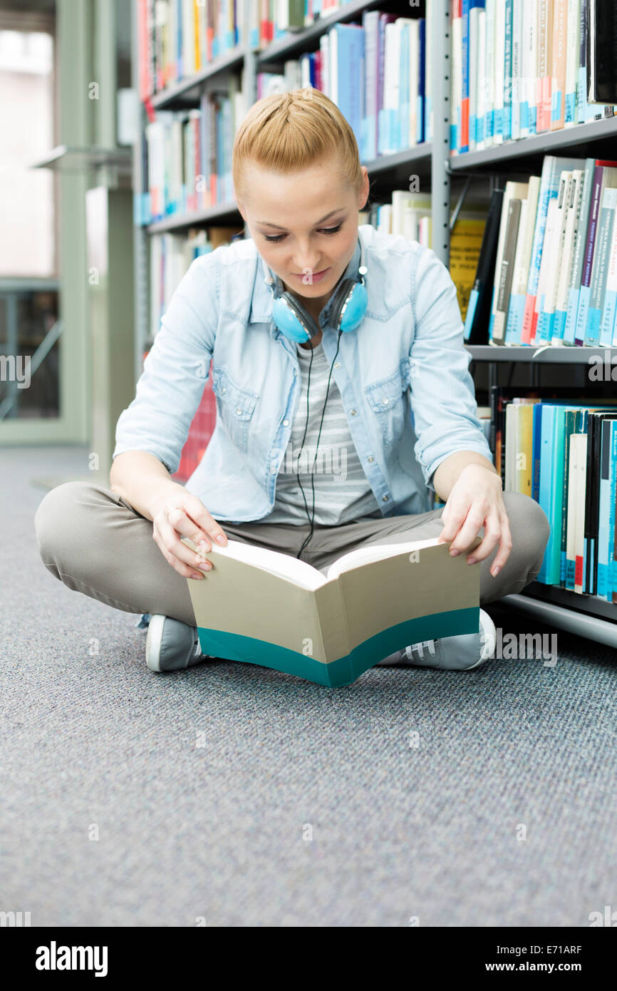 Student in a university library sitting on floor reading book Stock ...