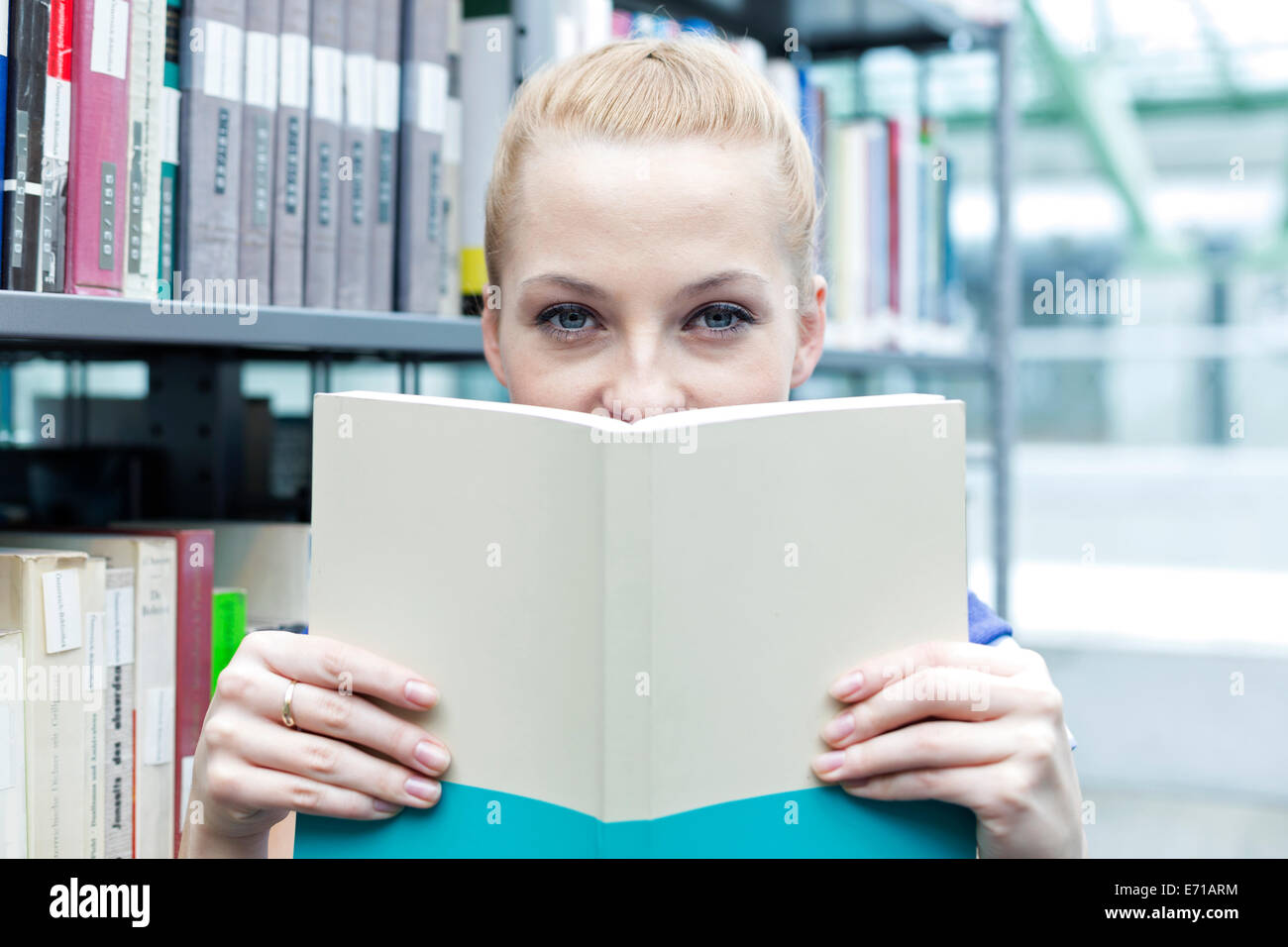 Student in a university library holding book Stock Photo - Alamy