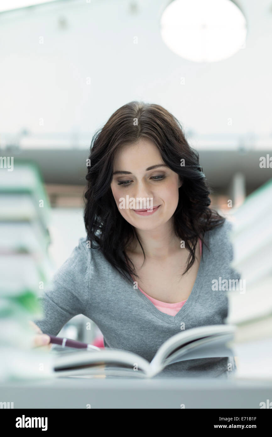 Student in a university library reading book Stock Photo - Alamy