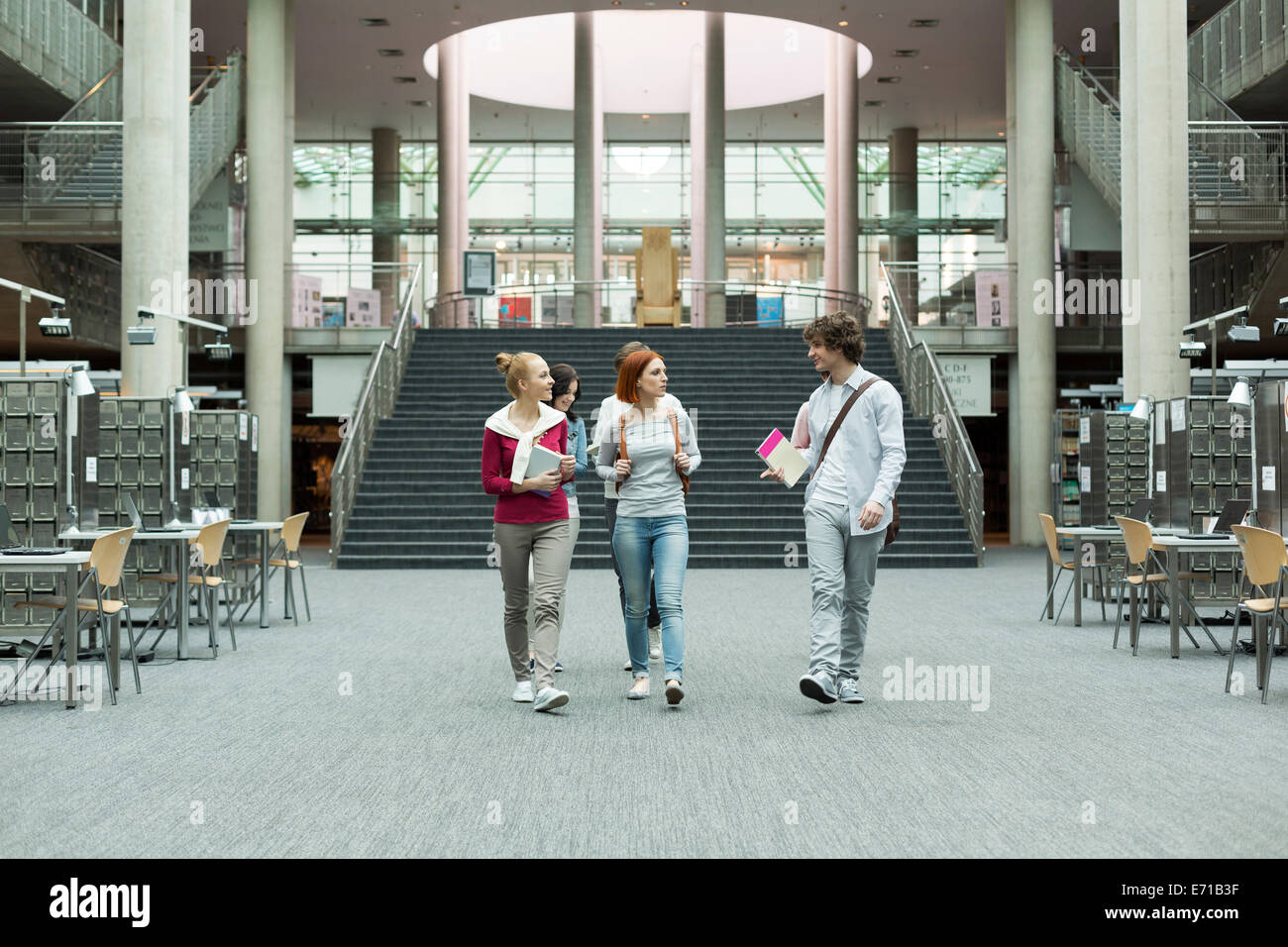 Group of students walking in a university library Stock Photo - Alamy