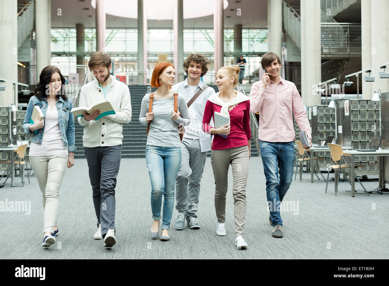 Group of students walking in a university library Stock Photo - Alamy