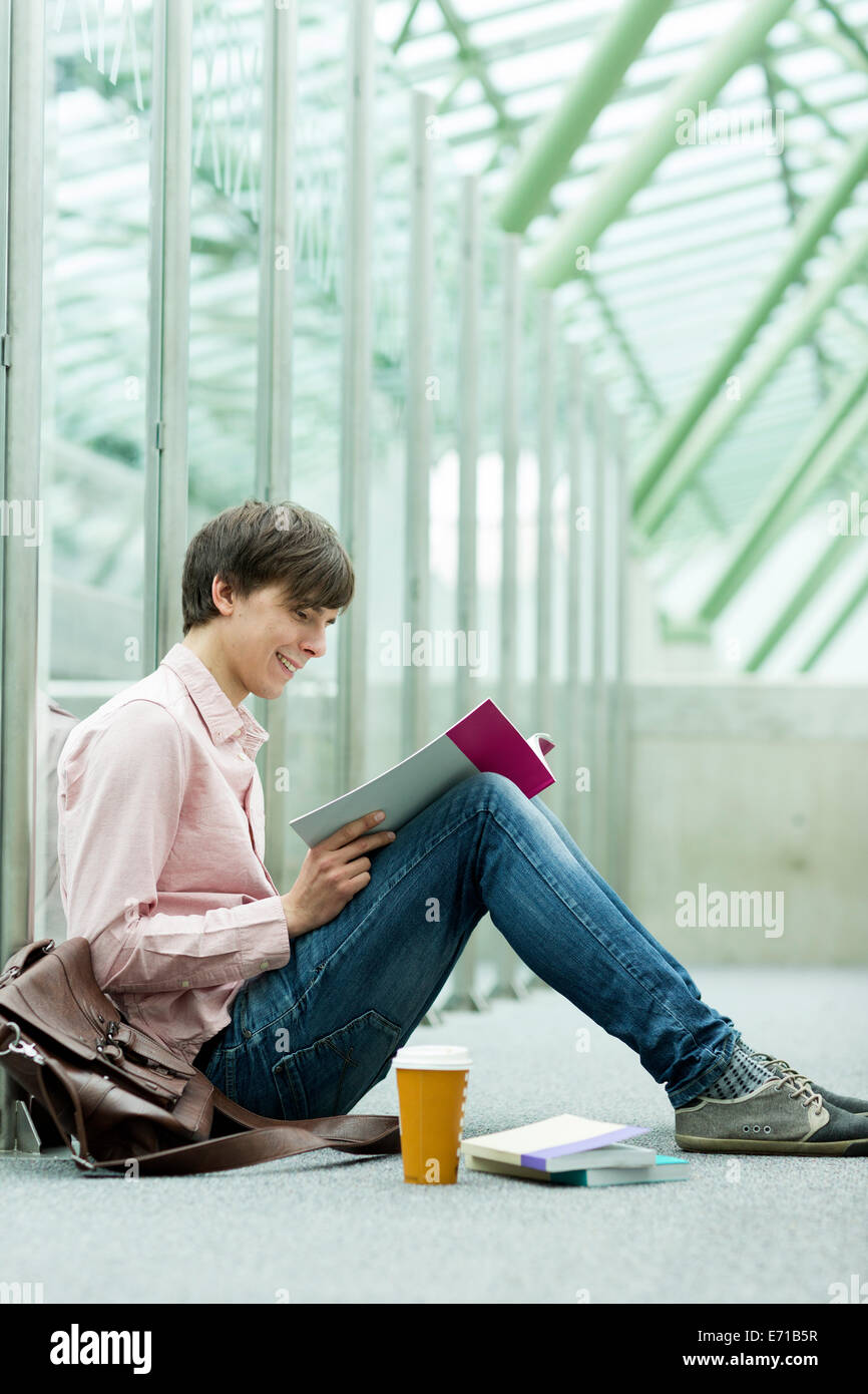 Student in a university library sitting on floor reading book Stock ...