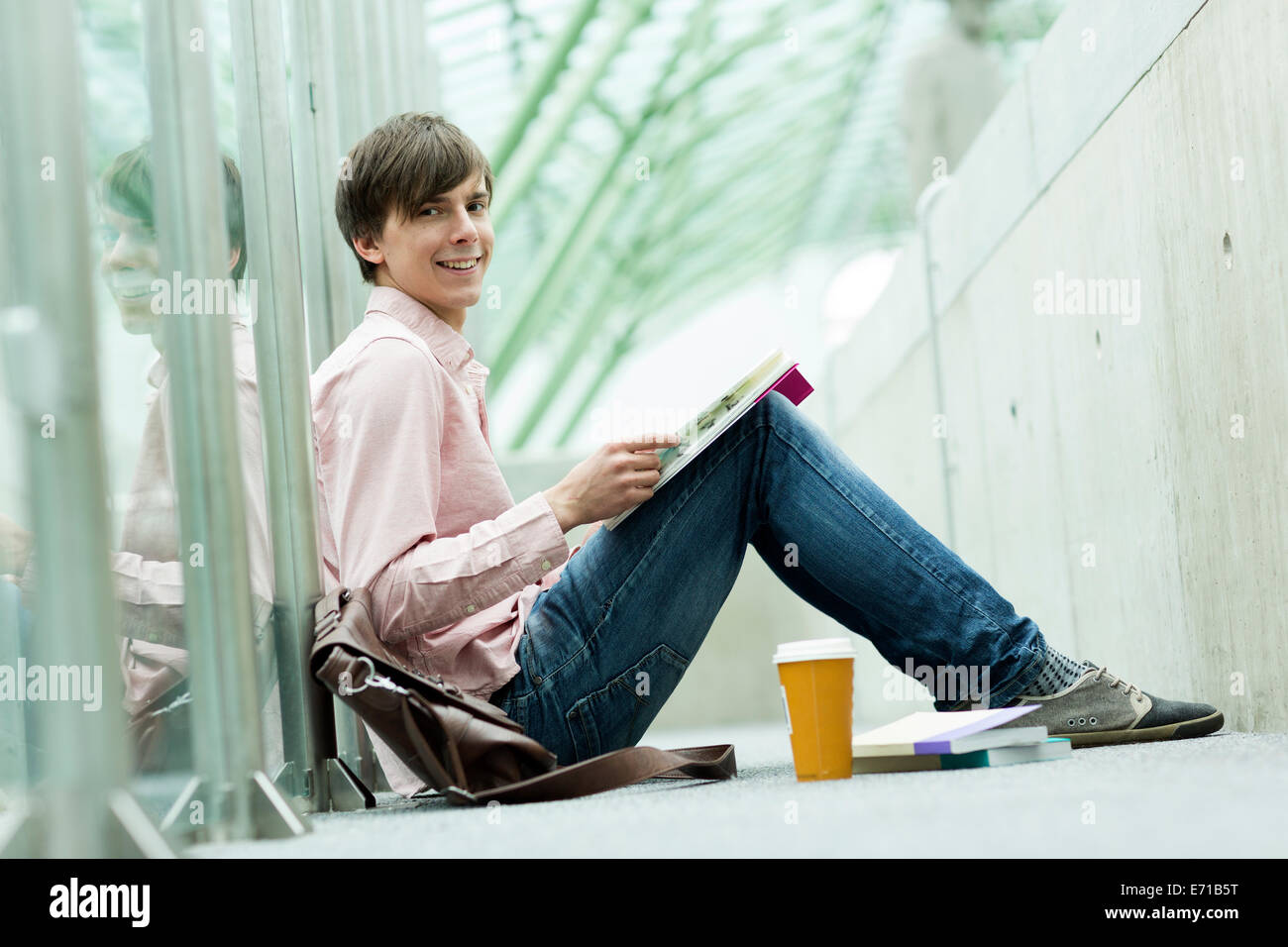 Student in a university library sitting on floor reading book Stock ...