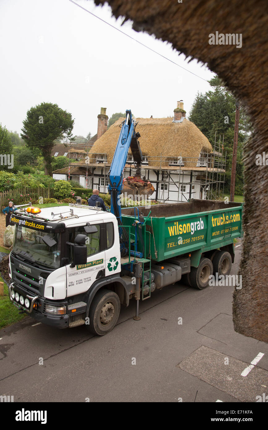 A grab truck with crane in action loading bricks and paving. Waste ...