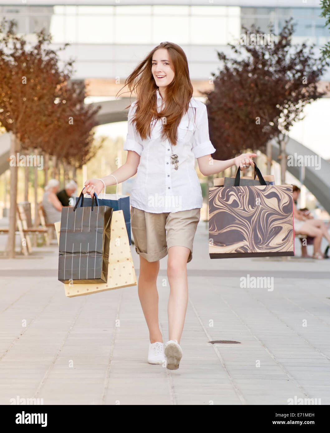 Smiling teenage girl looking happy after shopping, carrying shopping ...