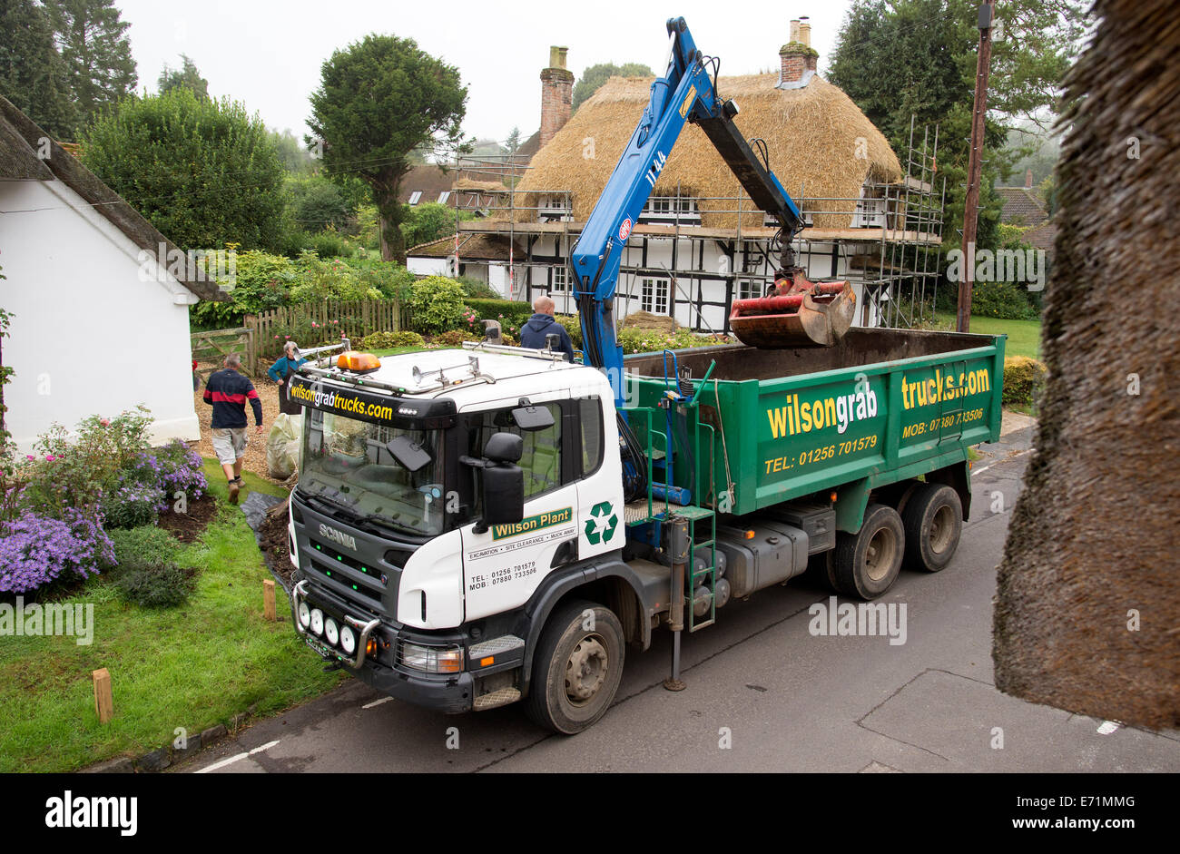 A grab truck with crane in action loading bricks and paving. Waste ...
