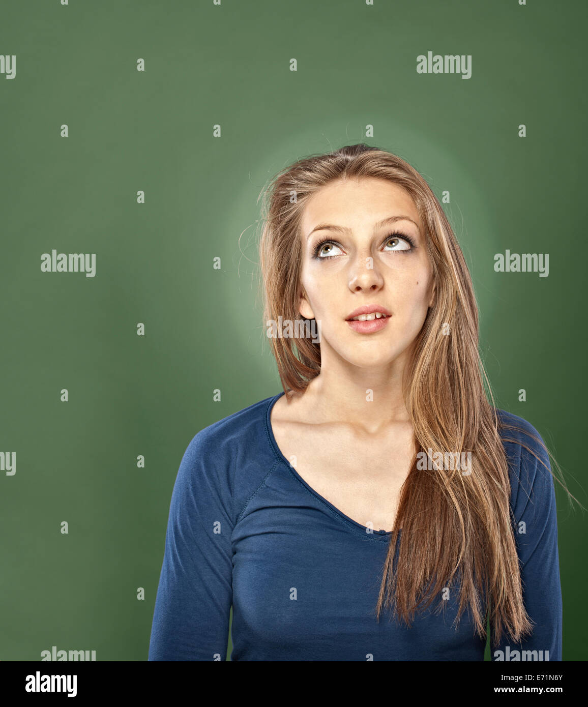 Beautiful student girl thinking and looking up. Green background, like ...