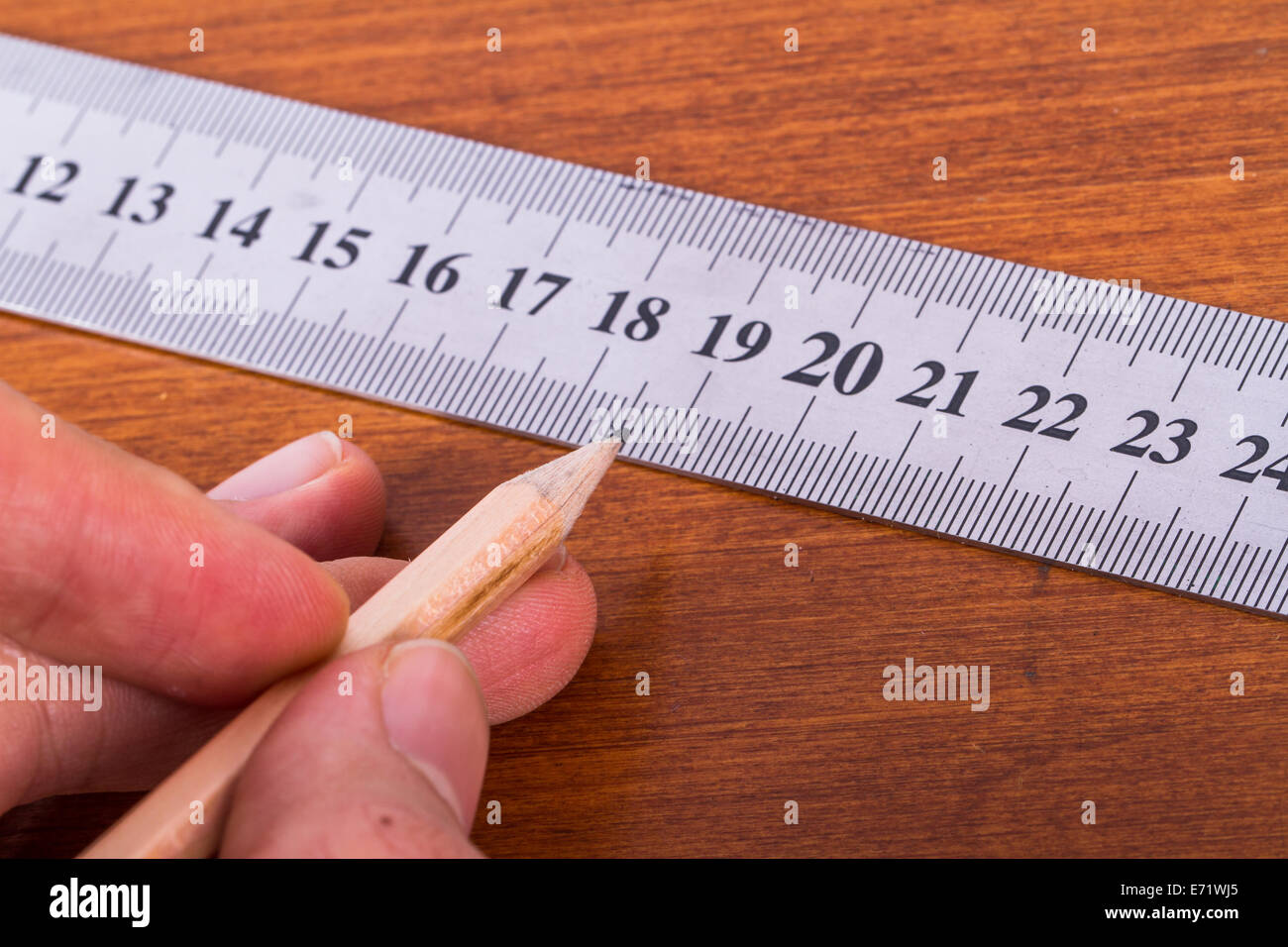 Macro view of hand holding wood pencil and steel ruler for engineering ...