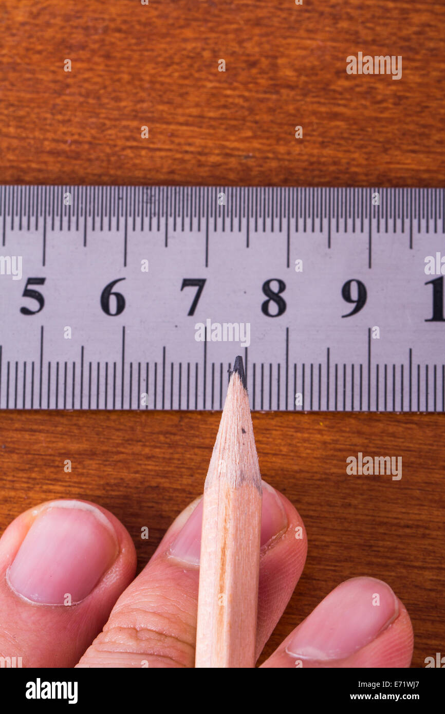 Macro view of hand holding wood pencil and steel ruler for engineering ...