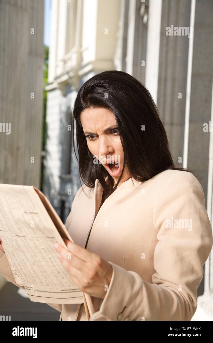 portrait of shocked woman reading financial newspaper Stock Photo - Alamy