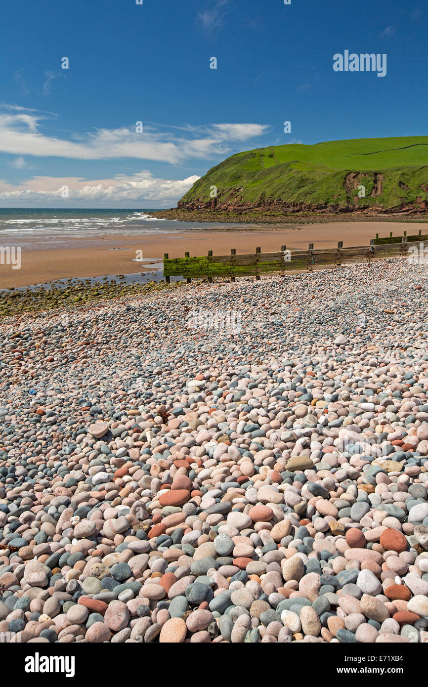 Deserted shingle beach with sand and sea beside green grass covered ...