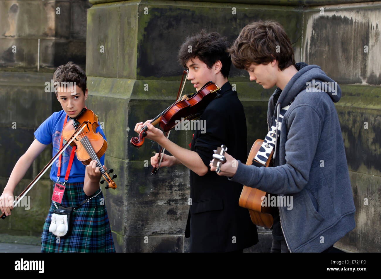 Three boys on fiddles and a guitar busking at the annual Festival ...