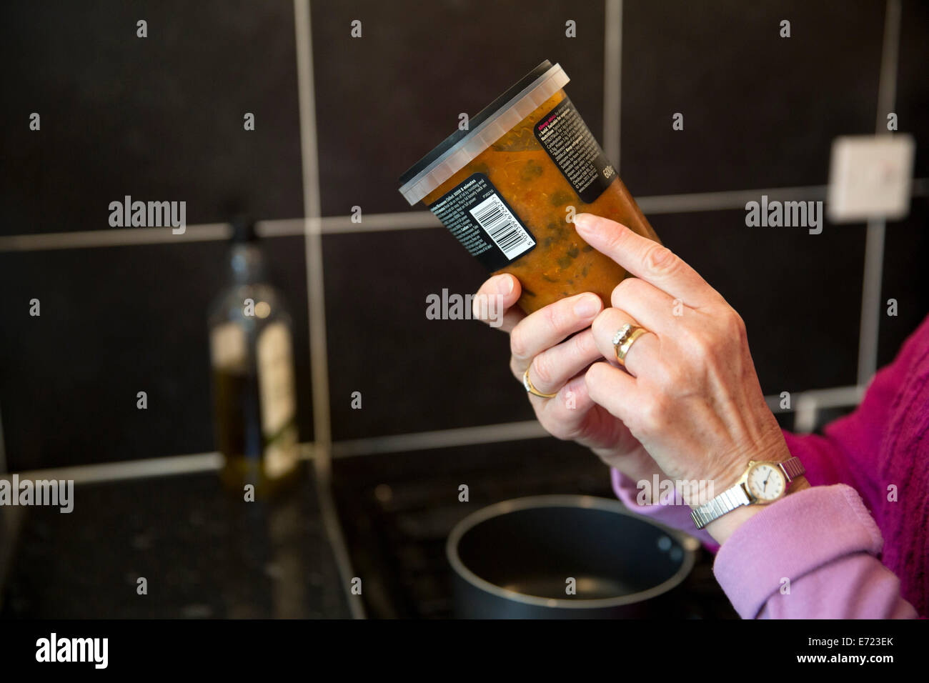 woman reading ingredients label on tub of prepared soup Stock Photo - Alamy