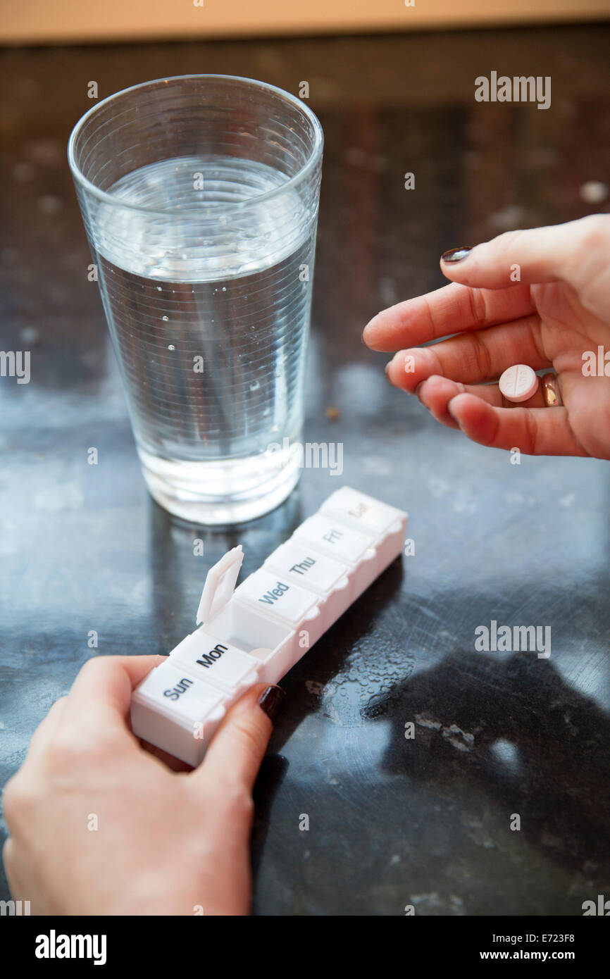 woman removing tablet from daily pill dispenser Stock Photo - Alamy