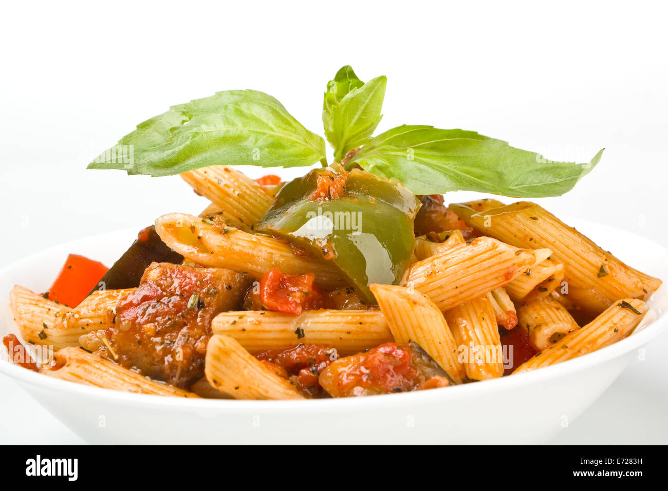 Mediterranean penne pasta in a white bowl with the garnish vegetables ...