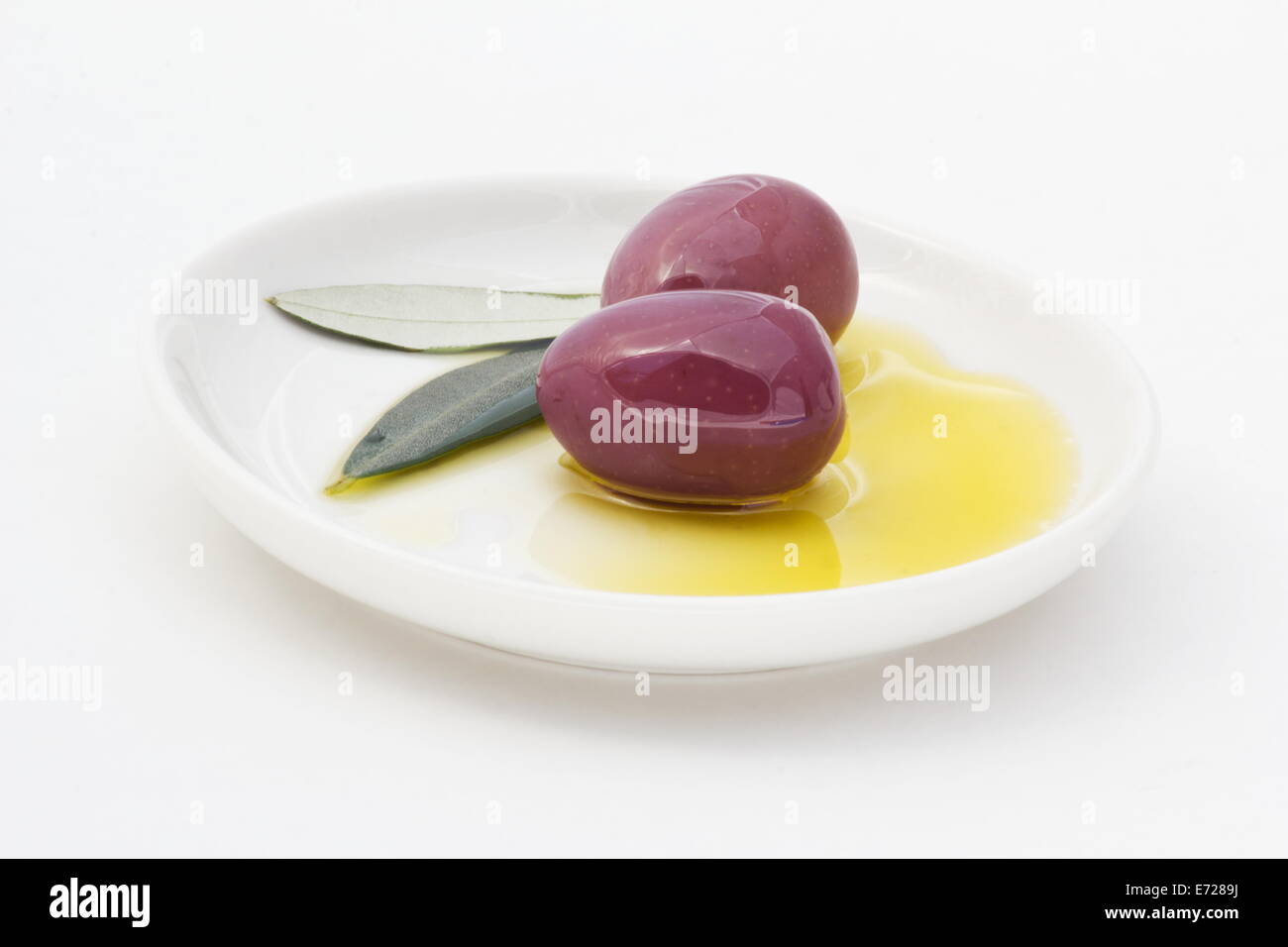 Two olives in olive oil on white background Stock Photo - Alamy
