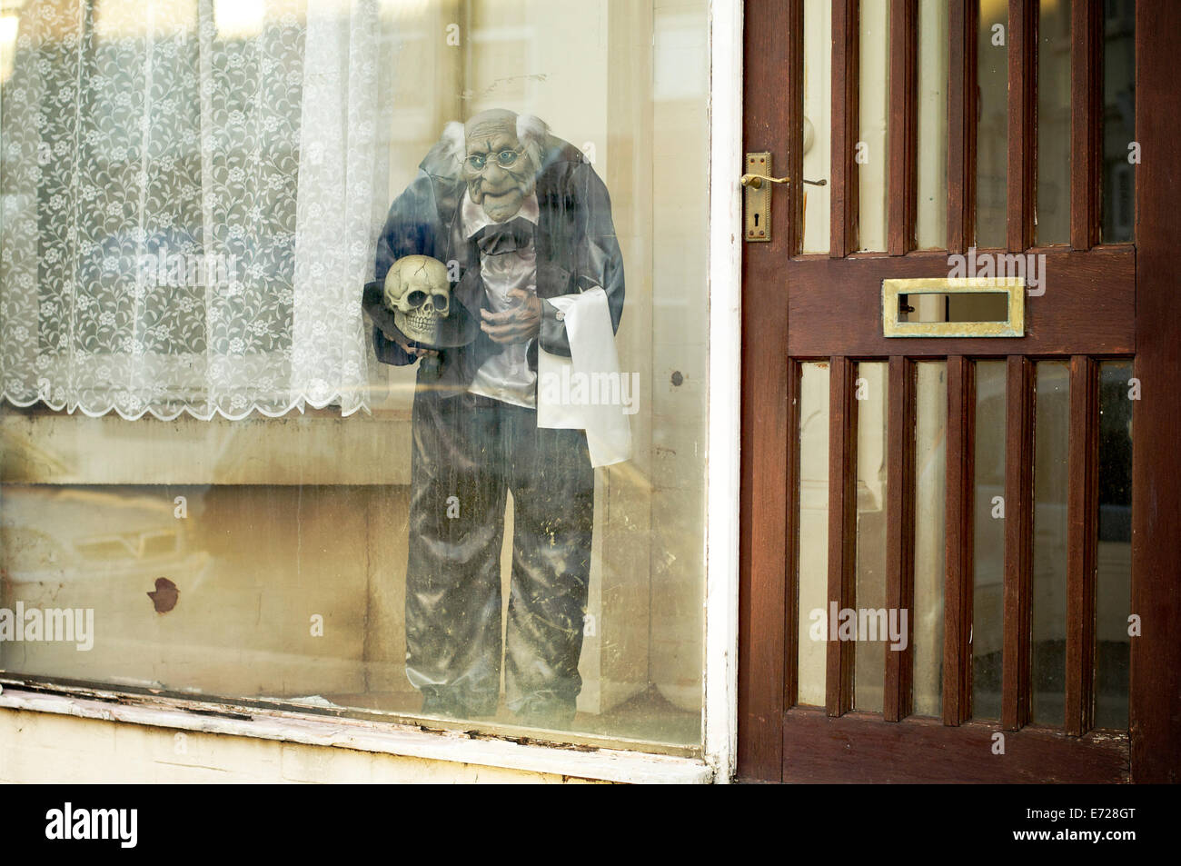 Scary butler stood in old hotel foyer holding human skull Stock Photo ...
