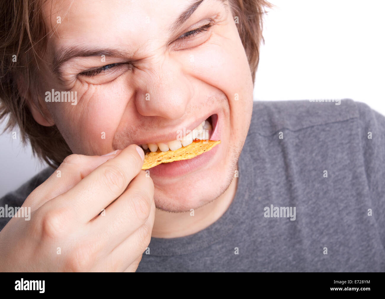 young man eating nachos with a funny grin close up Stock Photo - Alamy