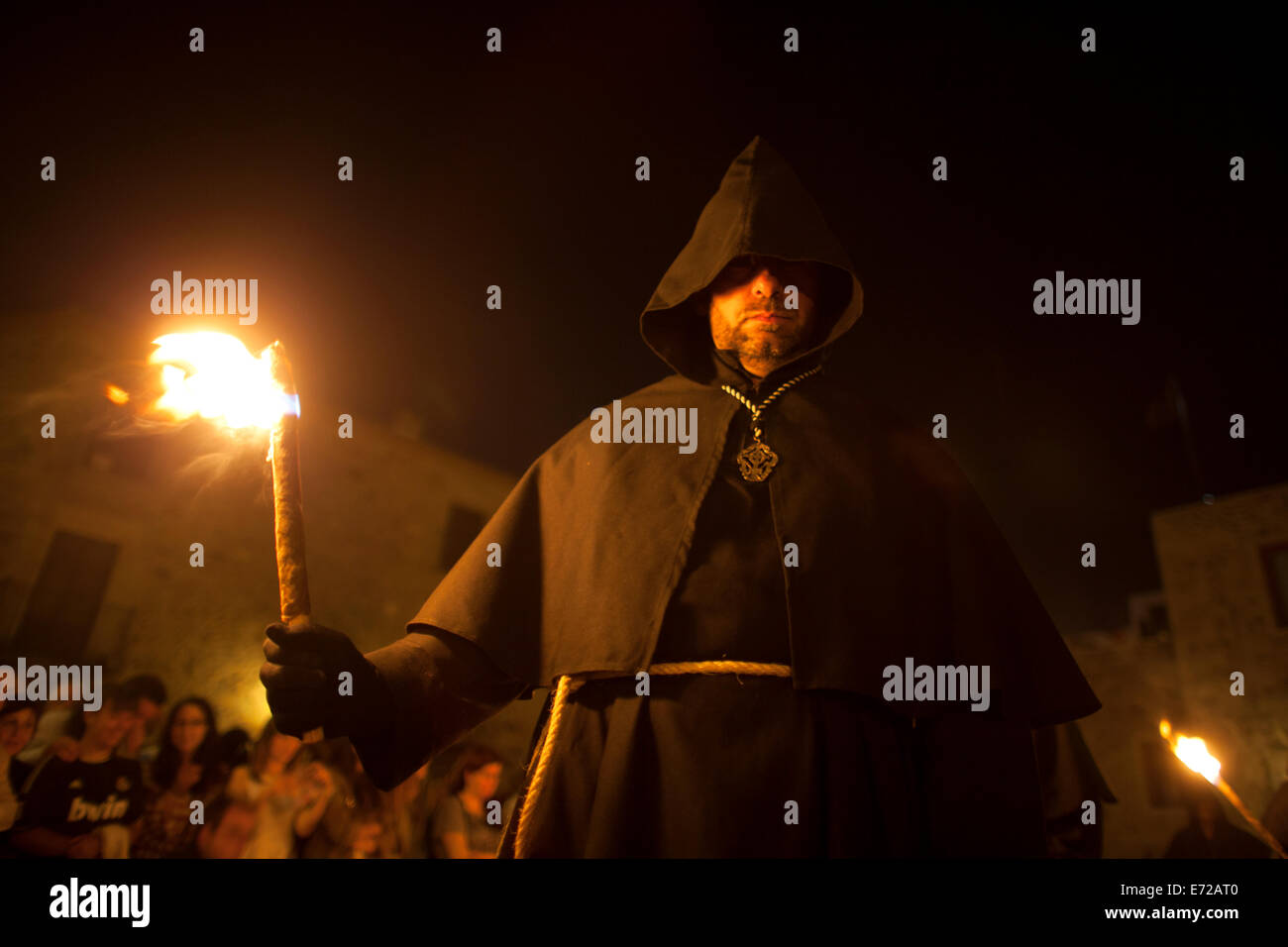 A penitent dressed as a Benedictine monk holds a torch at the ...