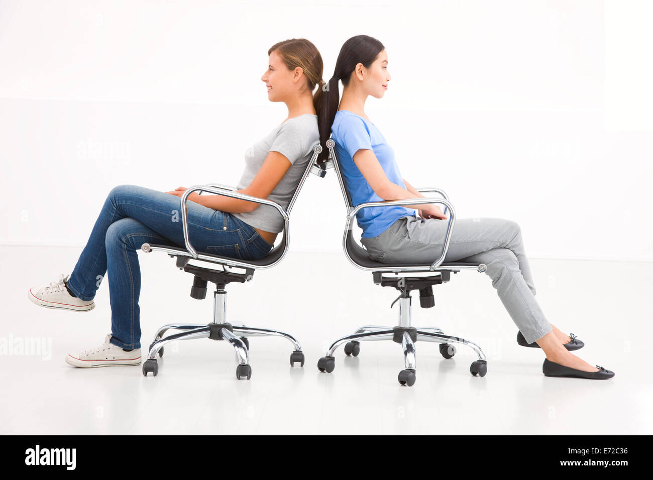 Two businesswoman sitting in chairs to back Stock Photo - Alamy