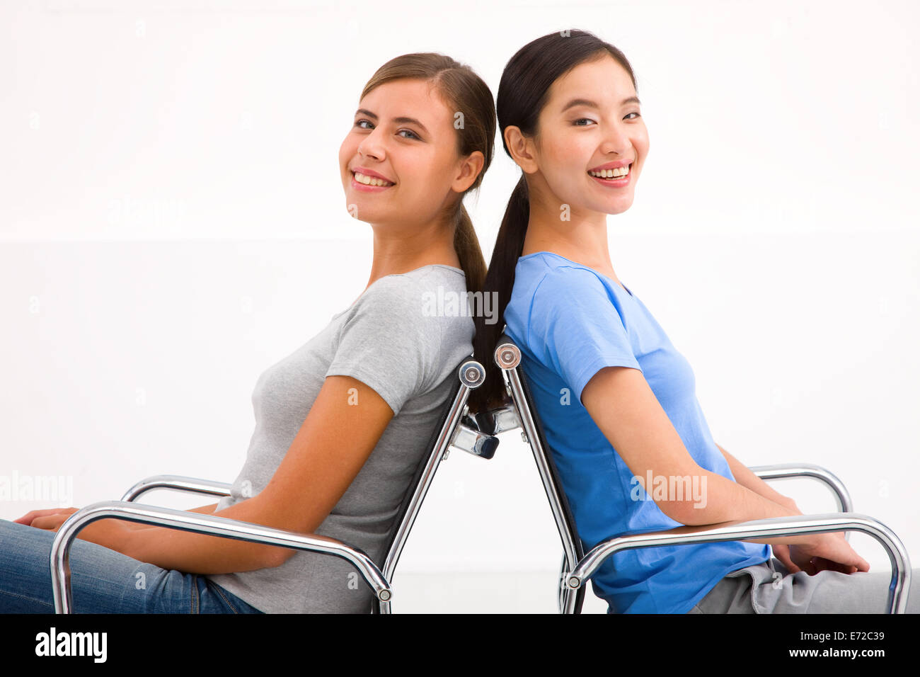 Two happy businesswoman sitting in chairs to back Stock Photo - Alamy