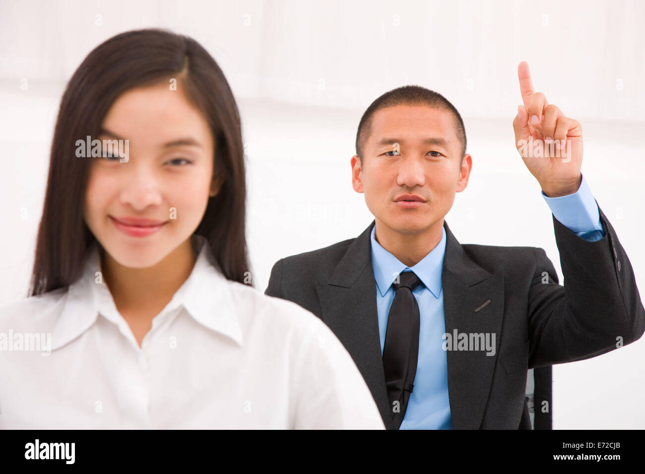 Businessman sitting behind businesswoman raising his finger Stock Photo ...