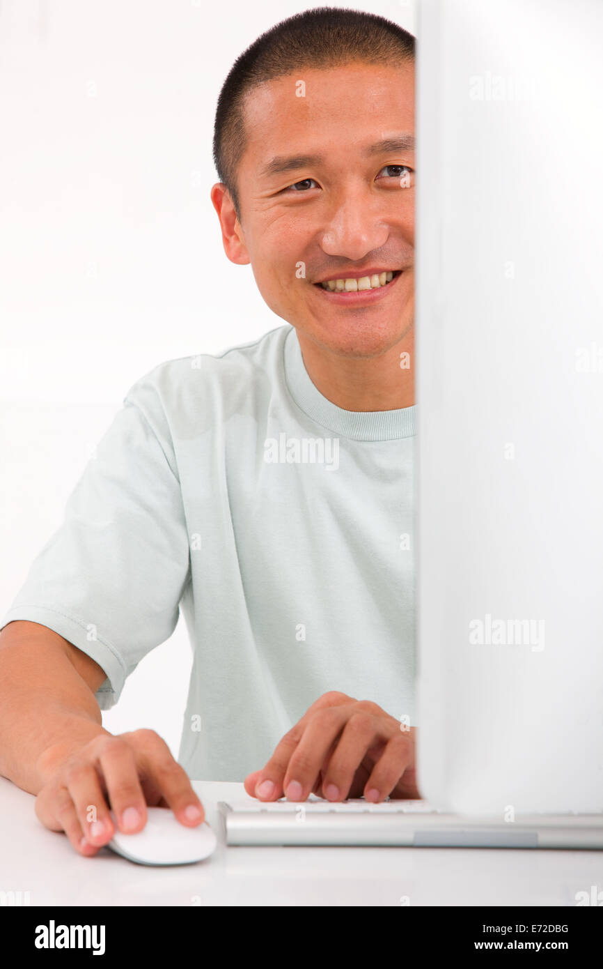 Smiling young asian man using computer Stock Photo - Alamy