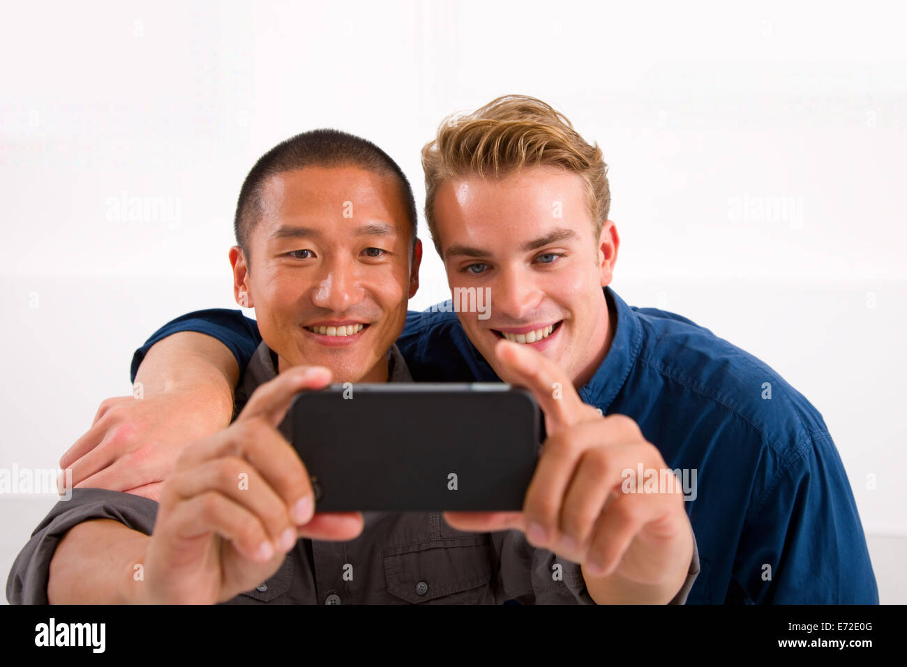 Two smiling young men taking self portrait with cell phone Stock Photo ...