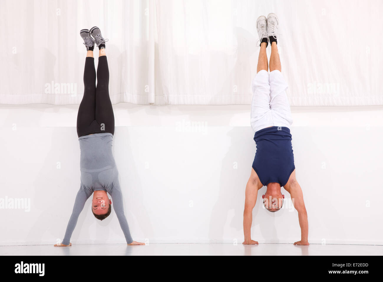 Man and woman doing handstand exercise in gym Stock Photo - Alamy