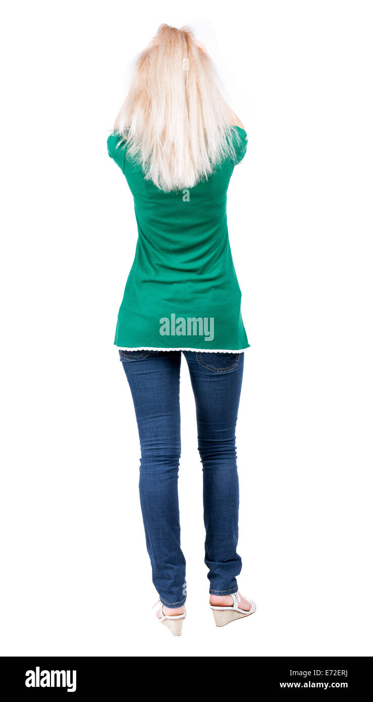 back view of standing young beautiful blonde woman. she shyly looks at ...