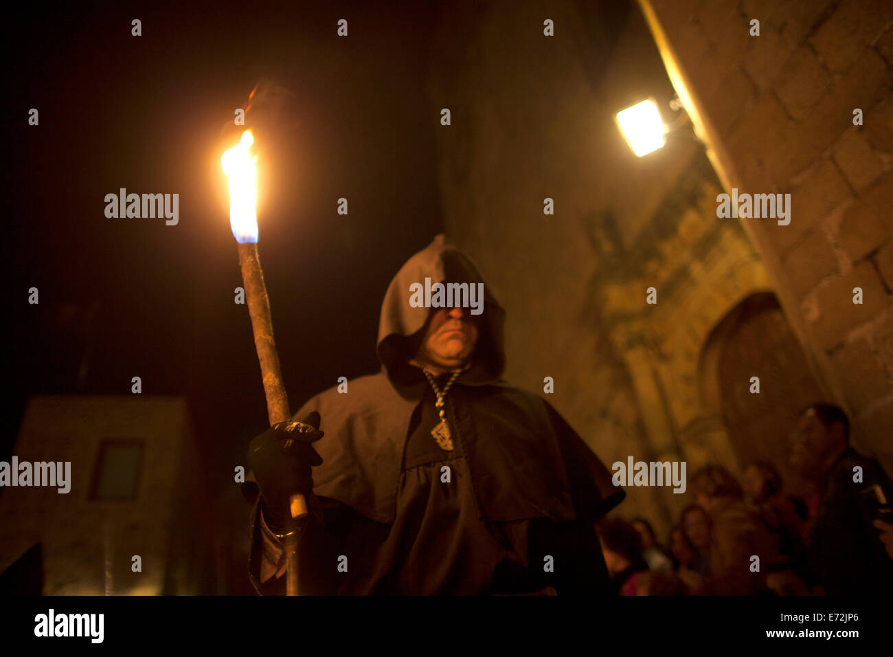 A penitent dressed as a Benedictine monk holds a torch at the ...