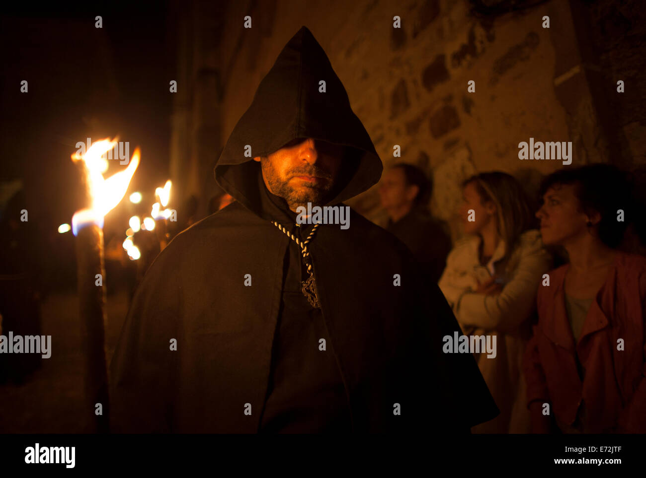A penitent dressed as a Benedictine monk holds a torch at the ...
